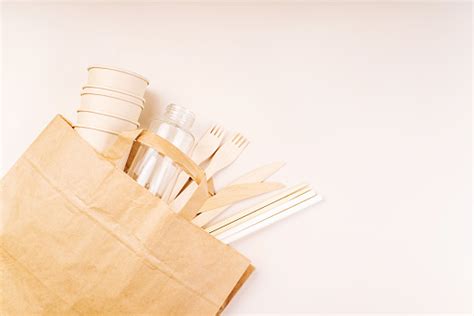 에코 공예 종이 식기 컵 패스트 푸드 용기 재활용 환경 친화적 인 개념 일회용 에코 칼 붙이 접시 숟가락 나이프 가벼운 배경에 포크 음식 배달을위한 종이 봉지를 제작하십시오