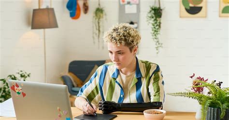 태블릿 화면에 스타일러스를 그린 젊은 진지한 그래픽 디자이너는 집에서 노트북 앞에서 스케치를 그리고 이미지를 수정합니다 사진 Unsplash의 랩톱 이미지