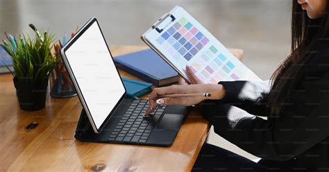 디지털 태블릿에서 작업하고 견본 샘플에서 색상을 선택하는 젊은 여성 그래픽 디자이너의 잘린 샷 사진 Unsplash의