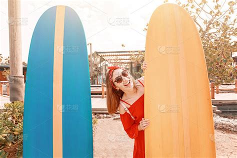 快乐的亚洲女孩与冲浪板休息在现代海滩附近的海