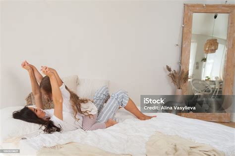 행복한 사랑하는 가족은 함께 침실에서 휴식을 취하고 즐기고 있습니다 어머니와 그녀의 귀여운 유치원 딸 소녀 잠옷에 놀고 아침에 흰색 침대에서 껴안고 행복한 어머니의 날 2