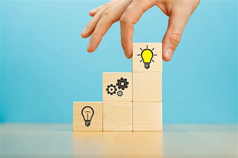 파란색 배경에 기어와 전구 아이콘이있는 나무 블록 피라미드를 손으로 놓습니다 손에 대한 스톡 사진 및 기타 이미지 손 전등 개념 Istock