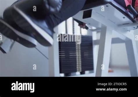 Female Legs Doing Exercise On The Simulator Girl Raises Her Legs With Weight On Them Woman