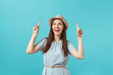 흥분된 젊은 우아한 여성 착용 드레스 밀 짚 여름 모자 파란색 배경에 고립 된 복사 공간에 인덱스 손가락을 가리키는의 초상화 사람들이 진심으 감정 라이프 스타일 개념 광고