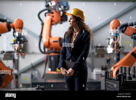 automation female engineer with tablet for programming robotic arm in