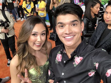 Two People Posing For A Photo In Front Of A Group Of People At An Event