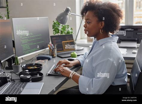 Side View Of Young African American Female Software Developer Using Computer Writing Code While