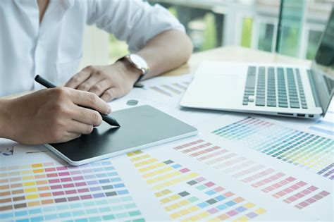 컴퓨터와 색상 견본 작업 젊은 그래픽 디자이너 현대 사무실에서 스타일러스 펜과 디지털 태블릿을 사용 하 여 창조적인 사람 작업 도구와 샘플 컬러 카탈로그를 사용 하 여