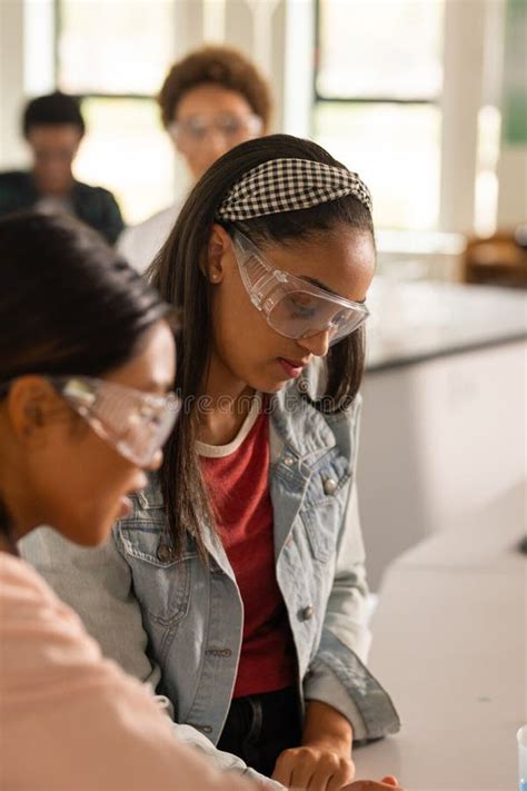 In High School Teenage Girls Wearing Safety Goggles Working On Science