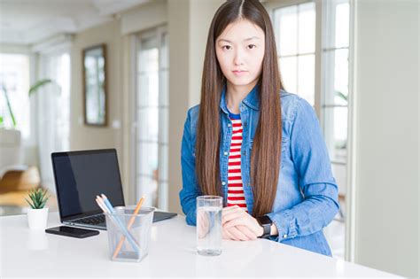 얼굴에 심각한 표정으로 컴퓨터 노트북을 사용하여 작업하는 아름다운 아시아 여성 카메라를 보는 간단하고 자연스러운 가정 생활에 대한 스톡 사진 및 기타 이미지 Istock