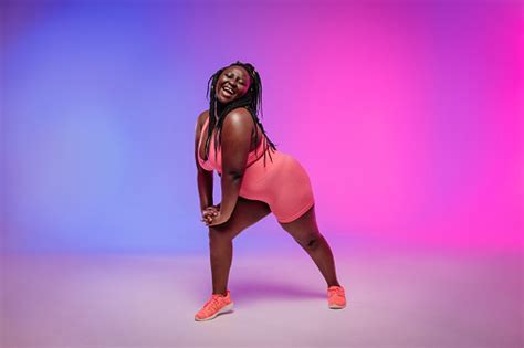 스포츠웨어를 입은 즐거운 플러스 사이즈 여성의 전체 길이는 운동하고 화려한 배경에 자신감을 보입니다 땋은 머리에 대한 스톡 사진 및 기타 이미지 Istock