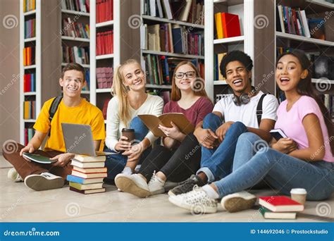 Group Of Diverse Teenage Classmates Sitting On Library Floor Stock