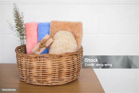 목욕 또는 샤워 컨셉을 위한 아로마테라피 스파 세트 나무 테이블에 고리버들 바구니에 꽃이 있는 사프 수건 루파 욕조 건강을 위해 자연에서 만든 손 복사 공간을 복사합니다