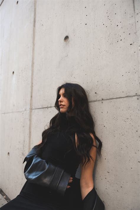 콘크리트 벽에 기대어 선 세련된 검은색 여성 · 무료 스톡 사진