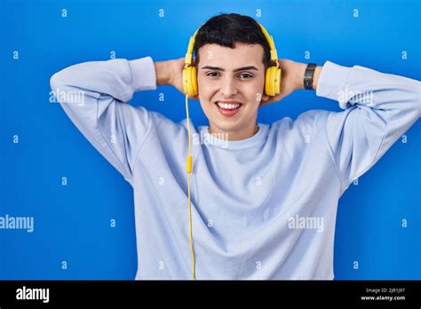 Non Binary Person Listening To Music Using Headphones Relaxing And Stretching Arms And Hands