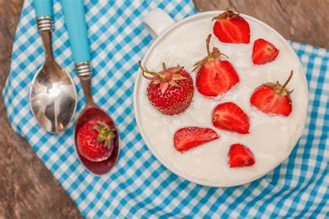 파란 숟가락 수건에 신선한 딸기와 요구르트 한 컵에 딸기 나무 바탕에 흩어져 클로즈업 평면도입니다 개념 건강 하 고 건강 한