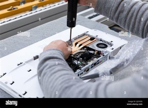 Photo Of Hands Of A Man Who Assembles A Computer Monitor System Block On An Conveyor Belt At A