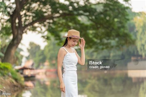 흰 드레스와 모자를 쓴 아시아 여성이 이른 아침 햇살을 받으며 매 핑 강가에서 휴식을 취하고 있습니다 30 34세에 대한 스톡 사진 및 기타 이미지 Istock