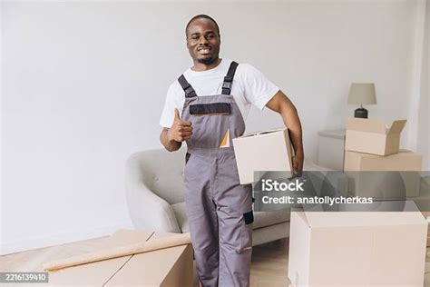 새 집에서 골판지 상자를 운반하는 동안 엄지 손가락을 치켜 올리는 아프리카 계 미국인 이사 20 24세에 대한 스톡 사진 및 기타 이미지 20 24세 가구 거실