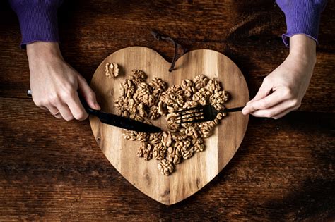 여성의 손은 칼을 들고 칼과 손에 포크 하트 모양의 나무 트레이에 호두를 벗깁니다 어두운 나무 배경 건강한 식생활 채식주의 갈색에 대한 스톡 사진 및 기타 이미지 Istock