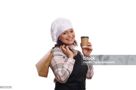 요리사 모자와 앞치마를 입은 웃는 여자 웨이트리스는 흰색 배경에 재활용 가능한 종이 봉지와 테이크아웃 뜨거운 음료를 들고 포즈를 취한다 개념에 대한 스톡 사진 및 기타