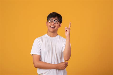 주황색 배경에 서 있는 젊은 아시아 남자가 손가락을 가리켰다 카메라를 보고 프리젠테이션 연설에 대한 스톡 사진 및 기타 이미지 프리젠테이션 연설 남자 사업가 주황색