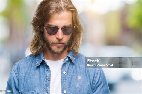 스마트폰 스마트 얼굴 심각한 생각에 자신감 표현 사용 하 여 메시지를 보내는 격리 된 배경 위에 긴 머리를 가진 젊은 잘생긴