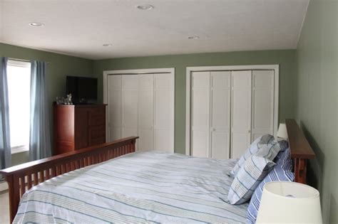 A Bedroom With Green Walls And White Closets Next To The Bed In Front Of It