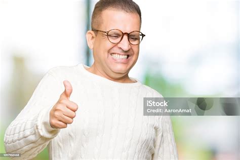 중세 아랍 남자 행복 엄지손가락 손으로 제스처를 하 고 격리 된 배경 위에 안경을 쓰고 승인 성공을 보여주는 카메라를 보고 하는 식 겨울에 대한 스톡 사진 및 기타 이미지