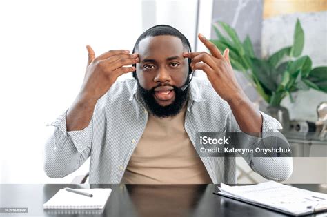 헤드셋 비즈니스 리더 또는 코치를 가진 기절한 당황한 아프리카 계 미국인 남자 화상 통화로 동료와 이야기하고 아이디어와 홍보에 대해 토론하고 혼란에 빠진 카메라를보고 손을
