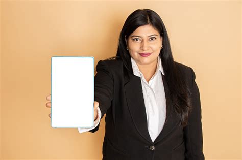 젊은 인도 사업가가 베이지색 배경 위에 격리된 광고를 넣기 위해 빈 디스플레이 화면이 있는 디지털 태블릿을 보여주는 양복을 입고 있다 기업 개념입니다 35 39세에 대한