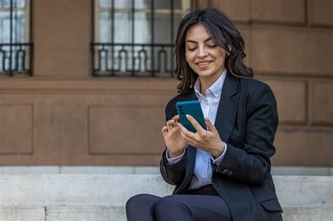 야외에서 스마트폰으로 화상 회의를 하는 자신감 넘치는 여성 사업가 젊은 임원은 도시 지역의 현대적인 사무실 센터에서 야외에서 대화를 나누고 공간을 복사한다 Brand