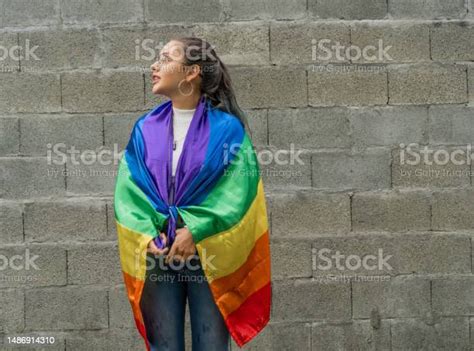 회색 배경에 게이 프라이드 깃발을 흔드는 야외 여성 회색 벽돌 배경에 게이 프라이드 깃발이 있는 젊은 여성의 초상화 18 19세에 대한 스톡 사진 및 기타 이미지 Istock