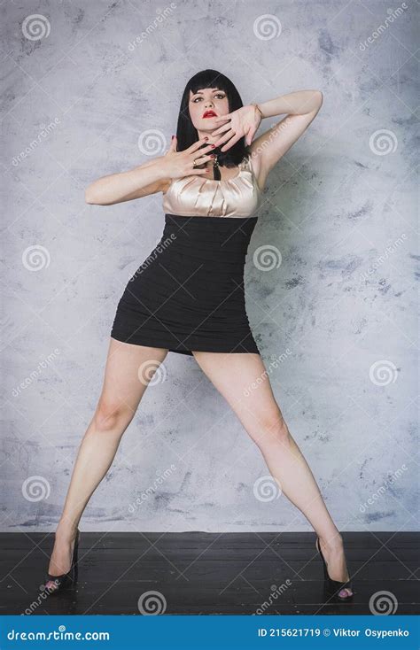 Brunette In A Short Dress Stands With Her Legs Wide Apart Stock Image Image Of Elegant Heels