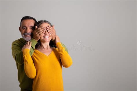 El Alegre Y Viejo Marido Europeo Cierra Los Ojos A Su Esposa Para Sorprender En El Fondo Gris De