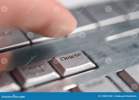 finger hand presses the delete button on the keyboard close up stock