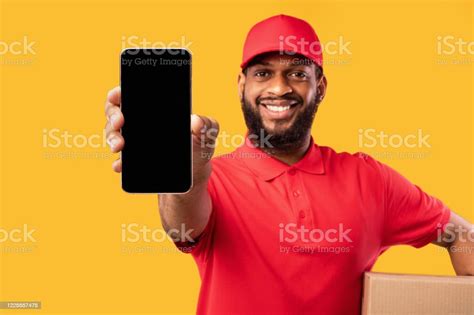 노란색 배경 위에 상자를 들고 스마트 폰 화면을 보여주는 배달 남자 개념에 대한 스톡 사진 및 기타 이미지 개념 고객 구매 Istock