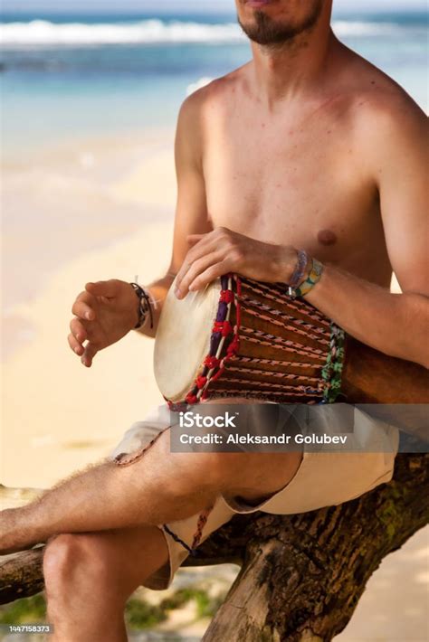 수염을 기른 청년 드러머 바다 배경의 열대 모래 해변에서 Djembe 드럼 악기로 리듬을 연주합니다 여행 휴가와 음악 휴식 개념 선택적 초점 텍스트 공간 복사 35 39세에
