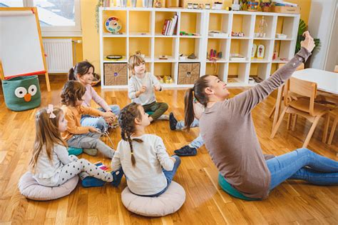 유치원 교사는 다양한 악기와 타악기를 사용하여 음악 수업을 하는 바닥에 앉아 있습니다 2 3 살에 대한 스톡 사진 및 기타 이미지 2 3 살 30 34세 4 5세