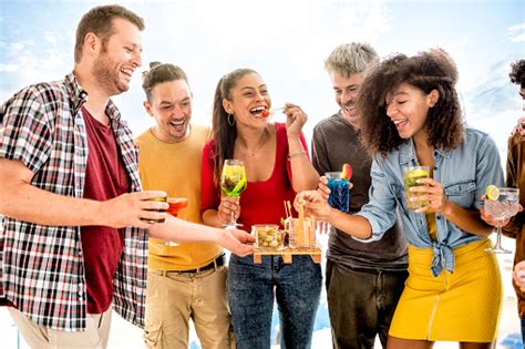 트렌디 한 바 옥상에서 해피 아워 동안 함께 마시고 먹는 행복한 혼합 인종 사람들 테라스에서 즐거운 시간을 보내고 일몰에