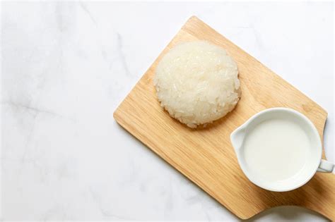 나무 트레이에 코코넛 밀크와 끈적 끈적한 쌀 일반적으로 잘 익은 망고 또는 두리안과 함께 봉사하십시오 태국 스타일의 열대 디저트 찹쌀은 열대 과일로 먹습니다 코코넛 우유에