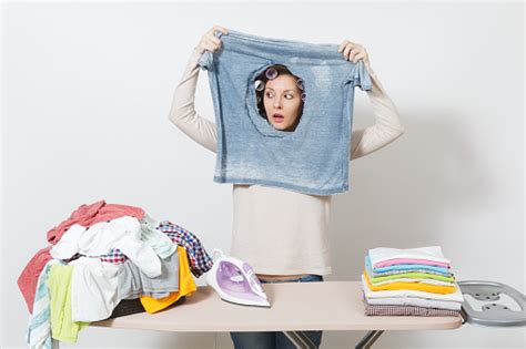 충격된 주부 들고 가벼운 옷에 머리에 컬러 셔츠 철 서 다리미 판에 의해 만들어진 구멍을 통해 보이는 불 흰색 배경에 고립 된 여자입니다 광고에 대 한 공간을 복사 합니다