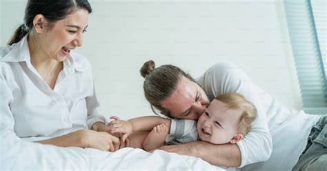 백인 부모는 침실에서 침대에서 귀여운 남자 아이와 놀고 있습니다 행복한 가족 매력적인 아름다운 돌보는 젊은 어머니와 아버지는 행복해 보이고 집에서 아침에 유아 아이