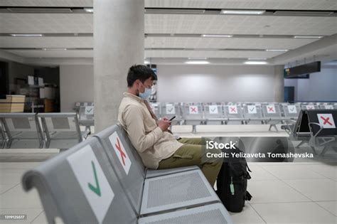 키프로스의 빈 공항에서 비행기를 기다리고 있습니다 빈 파포스 터미널에서 사회적 거리 마커와 의자에 앉아 남자 격리 중에 항공편이 취소되었습니다 코로나바이러스 항공사 붕괴