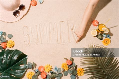 모자 큰 선글라스 레몬 조각과일 주스 다채로운 꽃 코코넛과 야자수 잎과 모래 해변 배경에 손가락으로 단어 여름을 쓰는 알 수없는 사람 여름과 휴일의 개념 복사 공간을