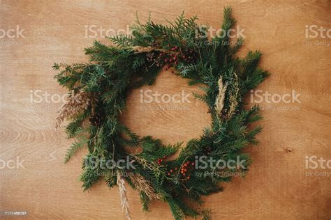 나무 테이블에 창조적 인 소박한 크리스마스 화환 평면 누워 시골 배경에 전나무 가지 열매 소나무 콘과 허브와 크리스마스 화환 공간을 복사합니다 계절 인사말 12월에 대한