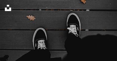 검은 색 바지를 입은 사람이 검은 색 나무 바닥에 서있는 검은 색과 흰색 운동화를 신고 사진 Unsplash의 무료 스케이트 이미지