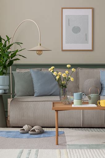 모형 포스터 프레임 모듈식 소파 나무 커피 테이블 파란색 베개 슬리퍼 식물 및 개인 액세서리가 있는 세련된 거실 인테리어의