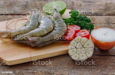 옆에 나무 절단 보드에 신선한 흰 새우 볼 나무 테이블에 해산물 메뉴를 요리에 대 한 원시 새우와 야채와 허브를 준비 집에서