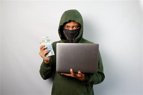 Premium Photo Hacker Wearing Green Hooded Holding A Laptop And Stealing Personal Data And